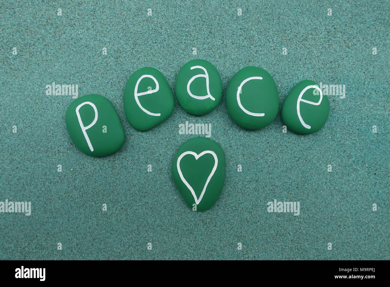 Peace word with green painted sea stones over green sand Stock Photo ...