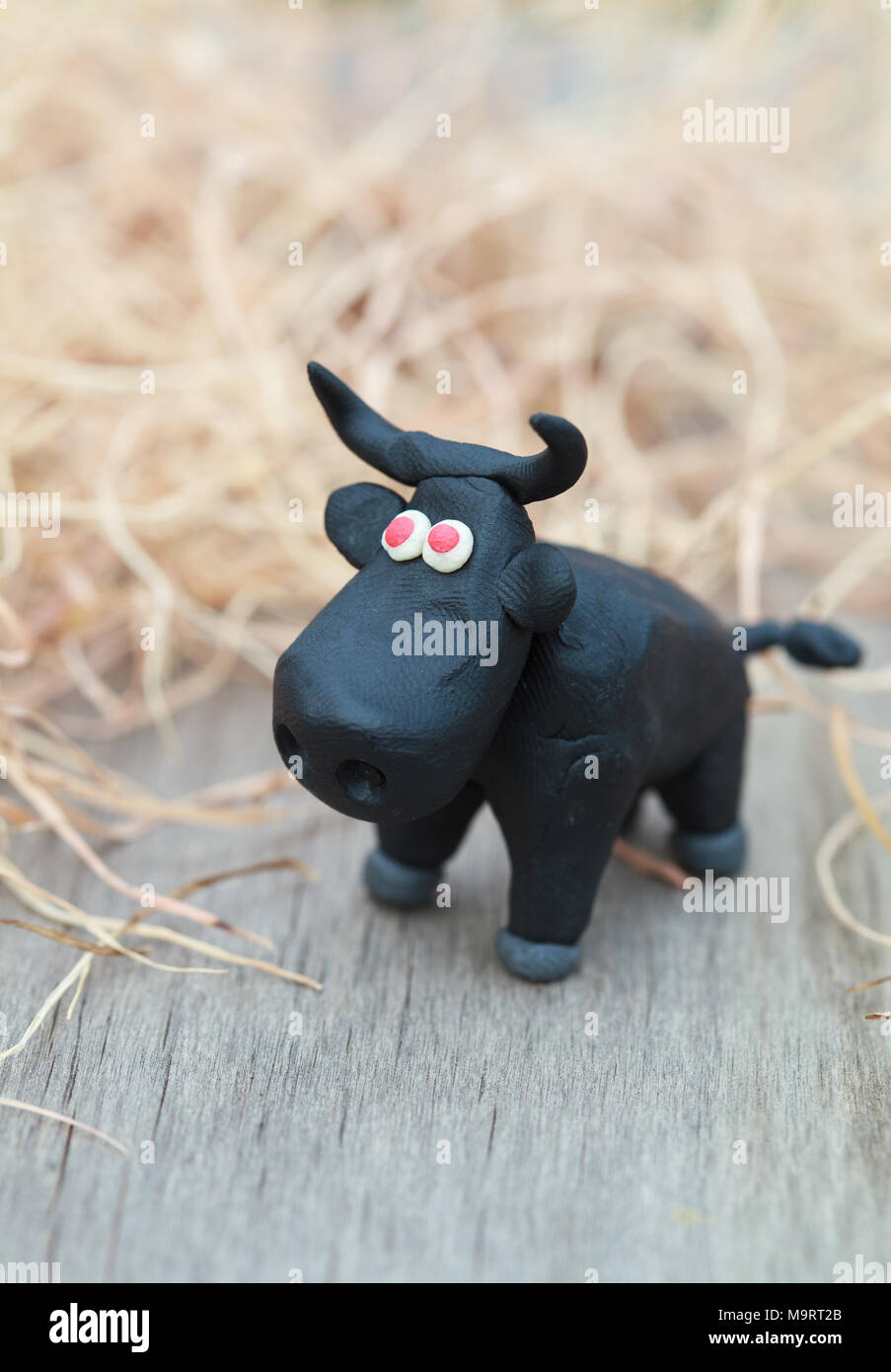 Plasticine world - little homemade black bull with red eyes stands on a ...