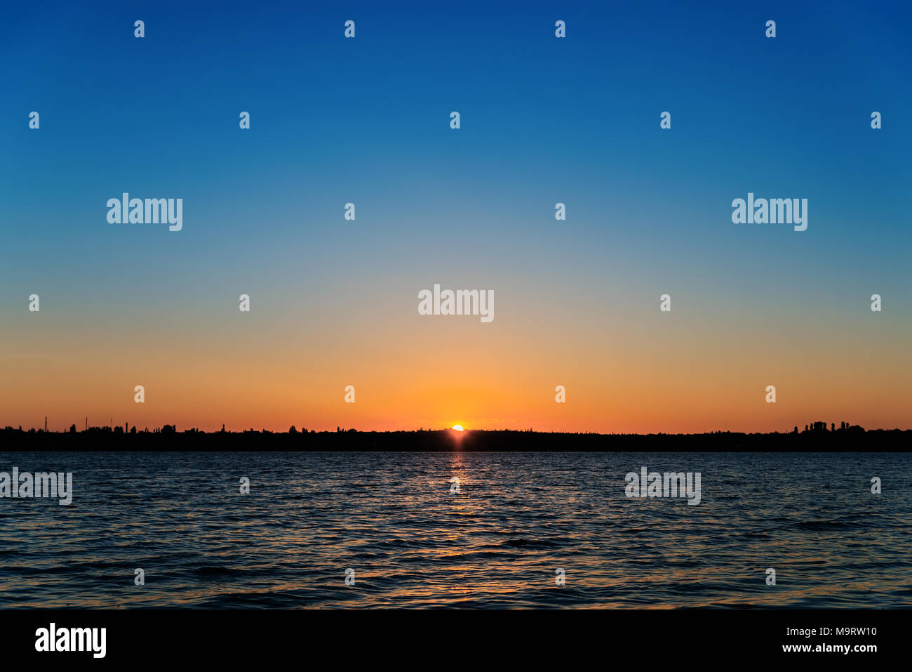 dark water in river and sunrise over it. first sun rays over river in ...