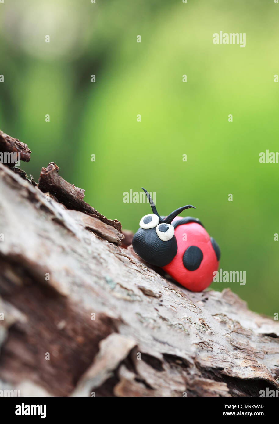 Plasticine world - little homemade red ladybird sitting on a old trank ...