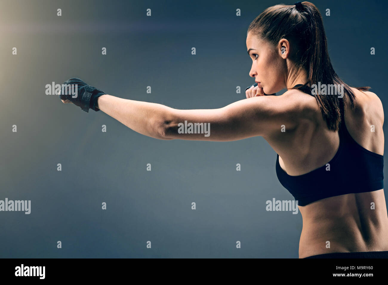 Side view of young sportswoman punching over background Stock Photo - Alamy