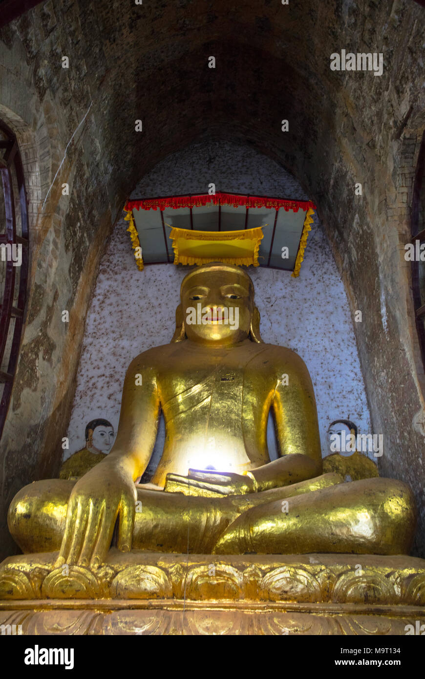A golden Buddha inside an ancient temple on the Irrawaddy river banks ...