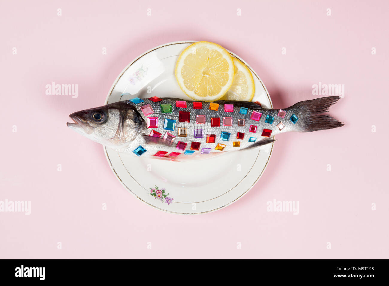 A bass fish covered with colorful precious stones inside a flower plate ...