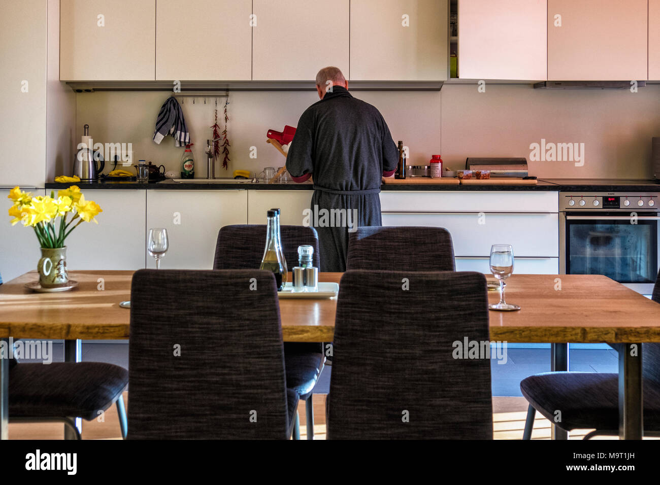 Senior elderly man in modern kitchen with wood dining table - preparing ...