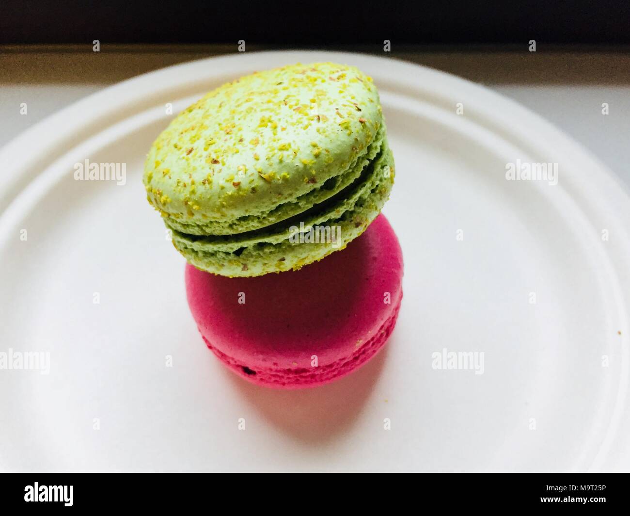 Different types of macaroons in motion falling on a white wooden ...