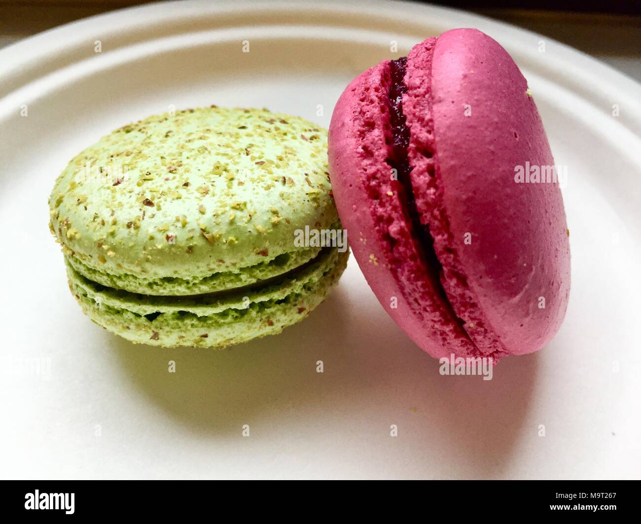 Different types of macaroons in motion falling on a white wooden ...