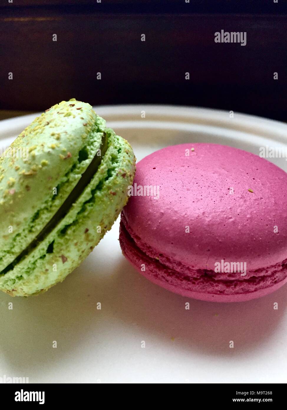 Different types of macaroons in motion falling on a white wooden ...