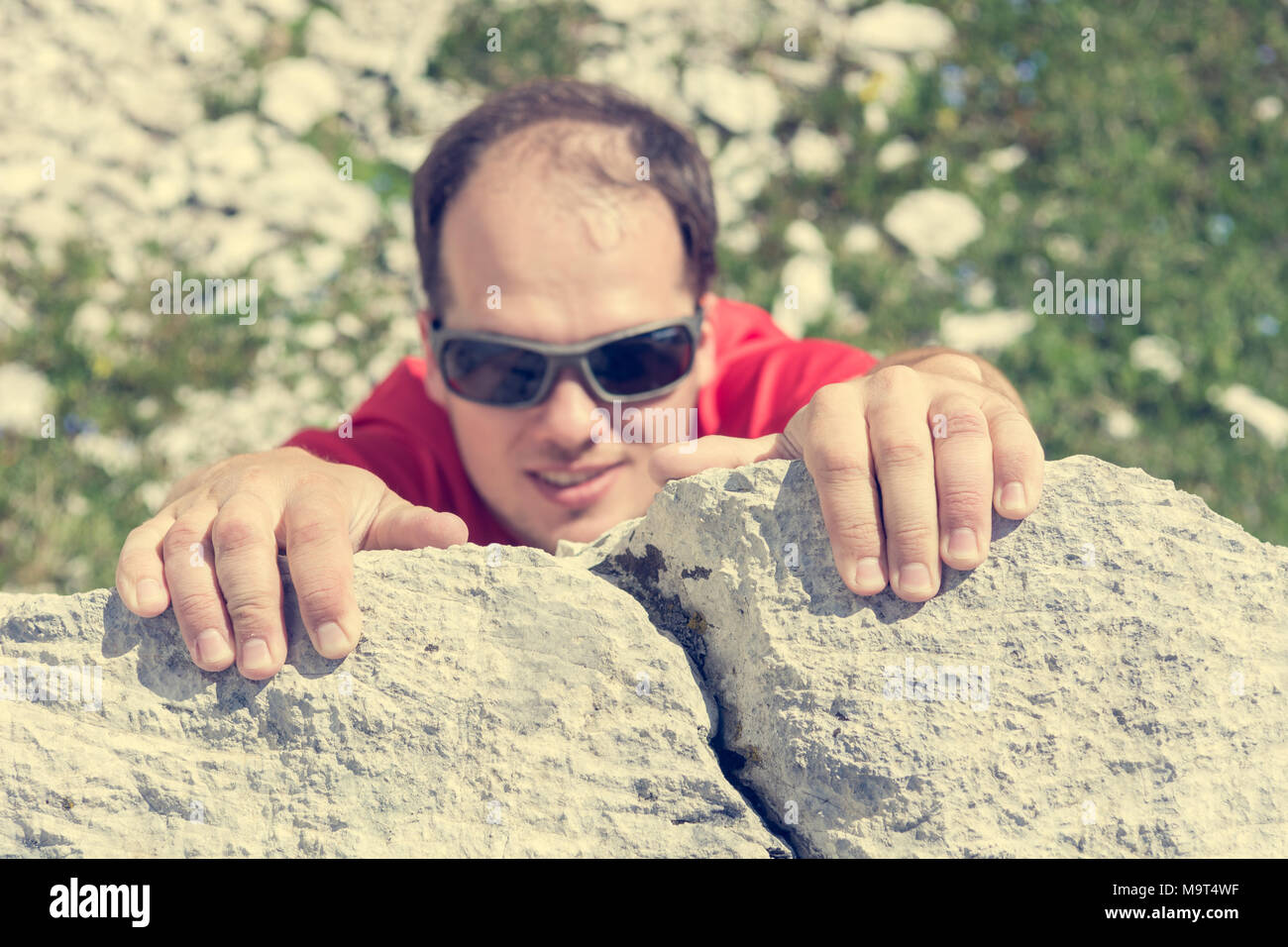 Male climber hanging from a rock Stock Photo - Alamy
