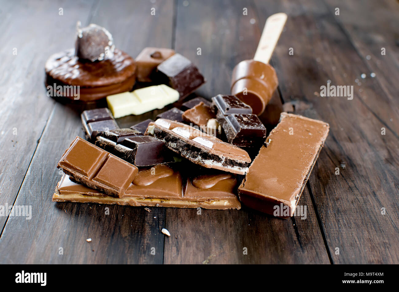 many pieces of different types of chocolate on old dark wooden table ...