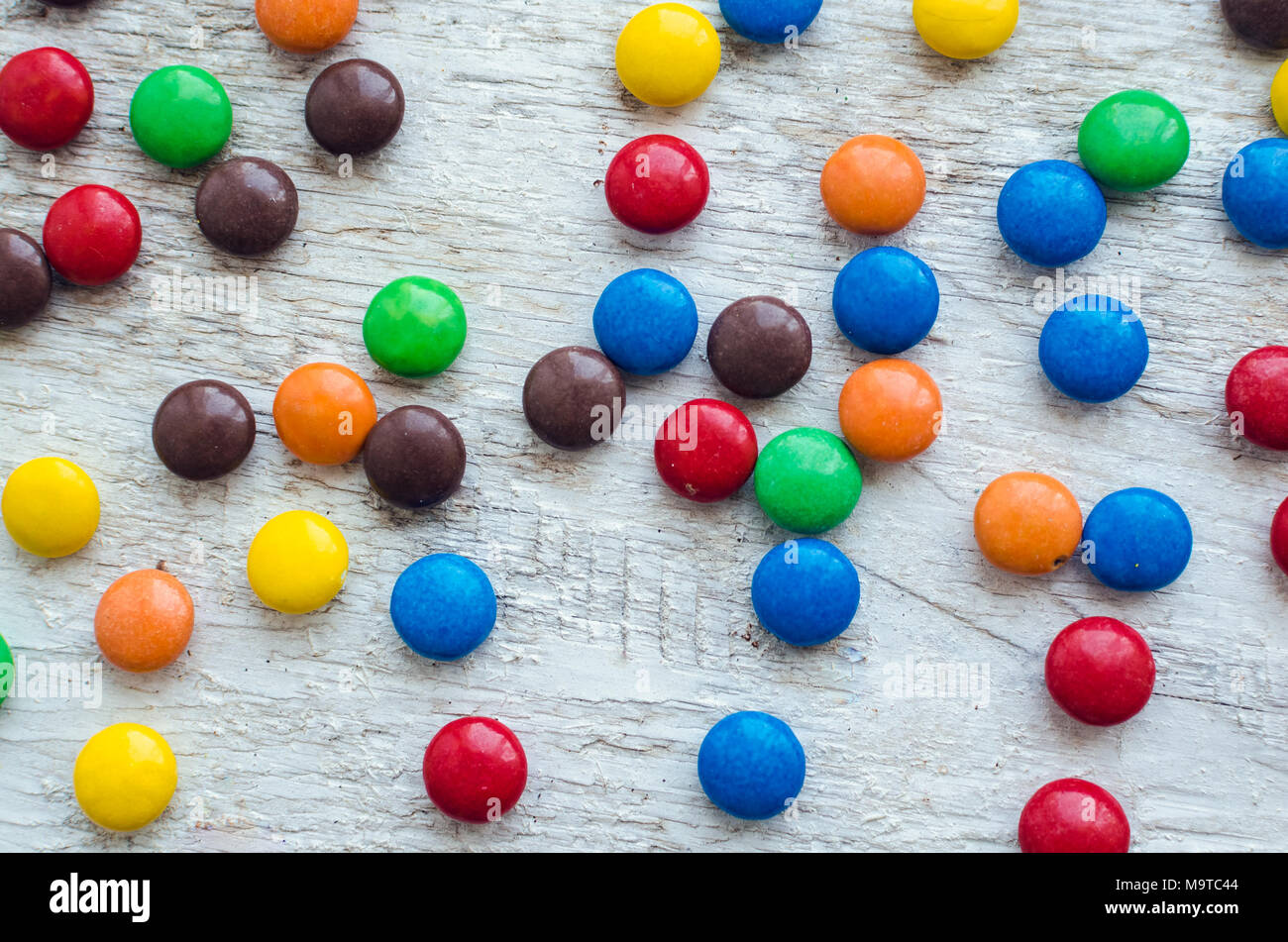 Colorful chocolate coated candies texture on white wooden background ...