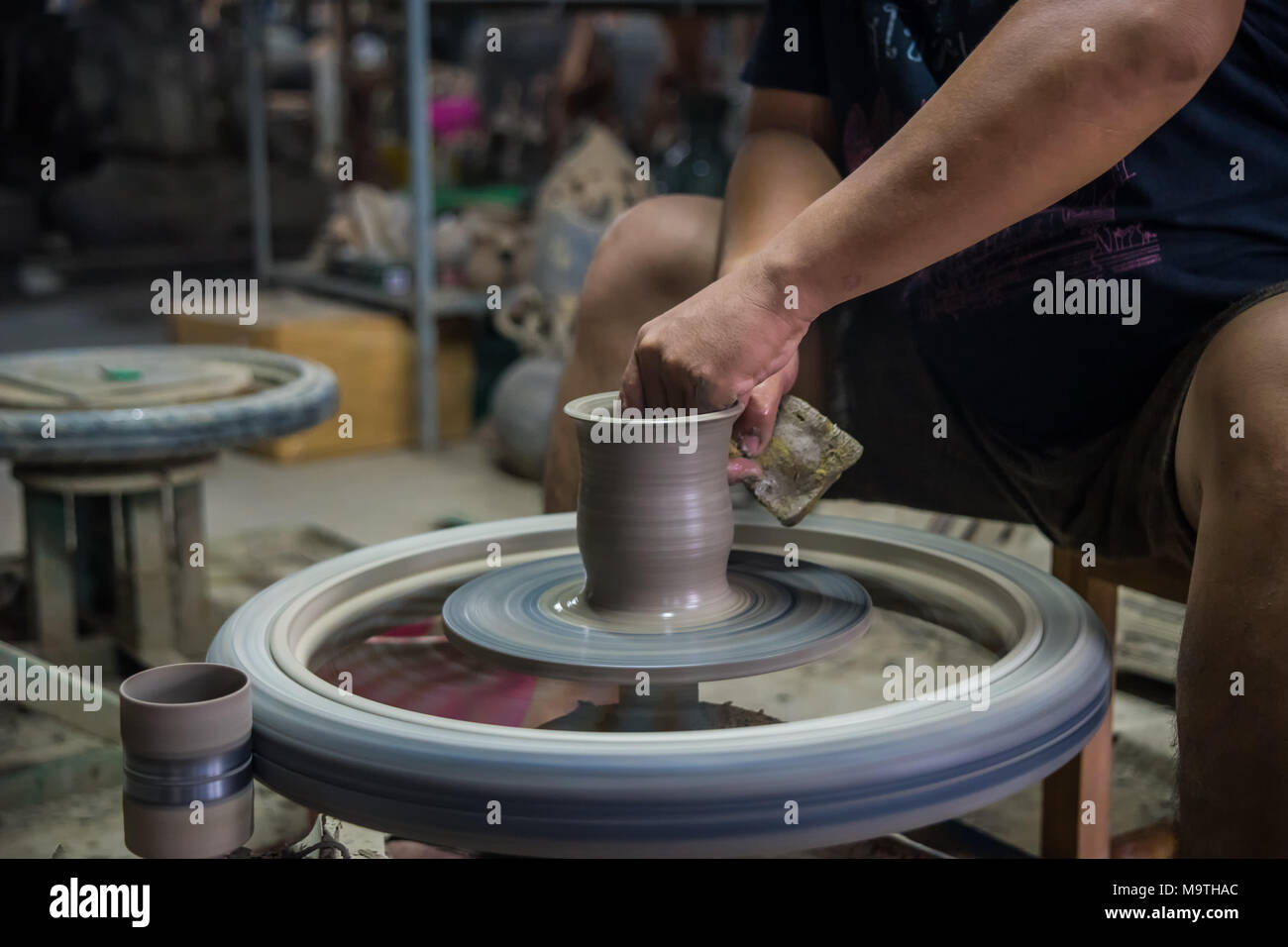 Craftsman creating ceramic pottery by using electrical motor rotation ...