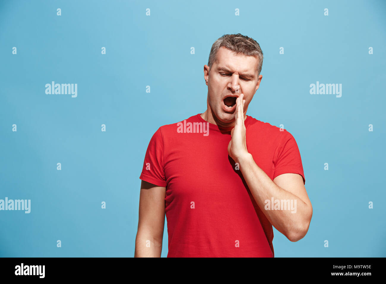 Beautiful bored man bored isolated on blue background Stock Photo - Alamy