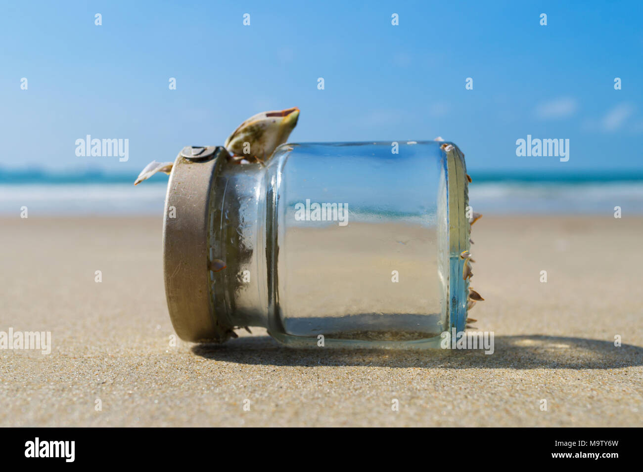 Empty glass bottle on sandy beach with blue sky and sea Stock Photo - Alamy