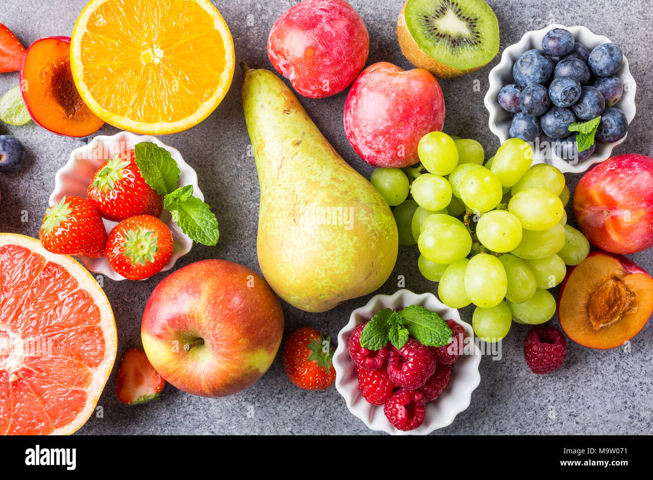 Fresh assorted fruits and berries on light gray background. Colorful ...