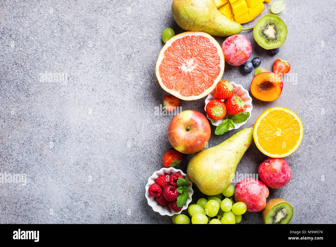 Fresh assorted fruits and berries on light gray background. Colorful ...