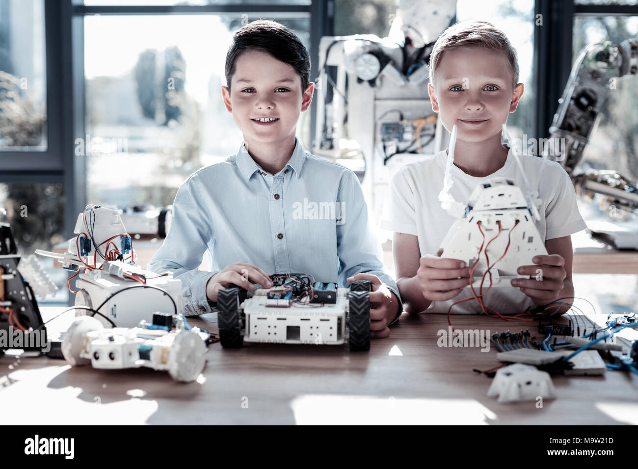 Joyful male friends constructing robotic machines Stock Photo - Alamy