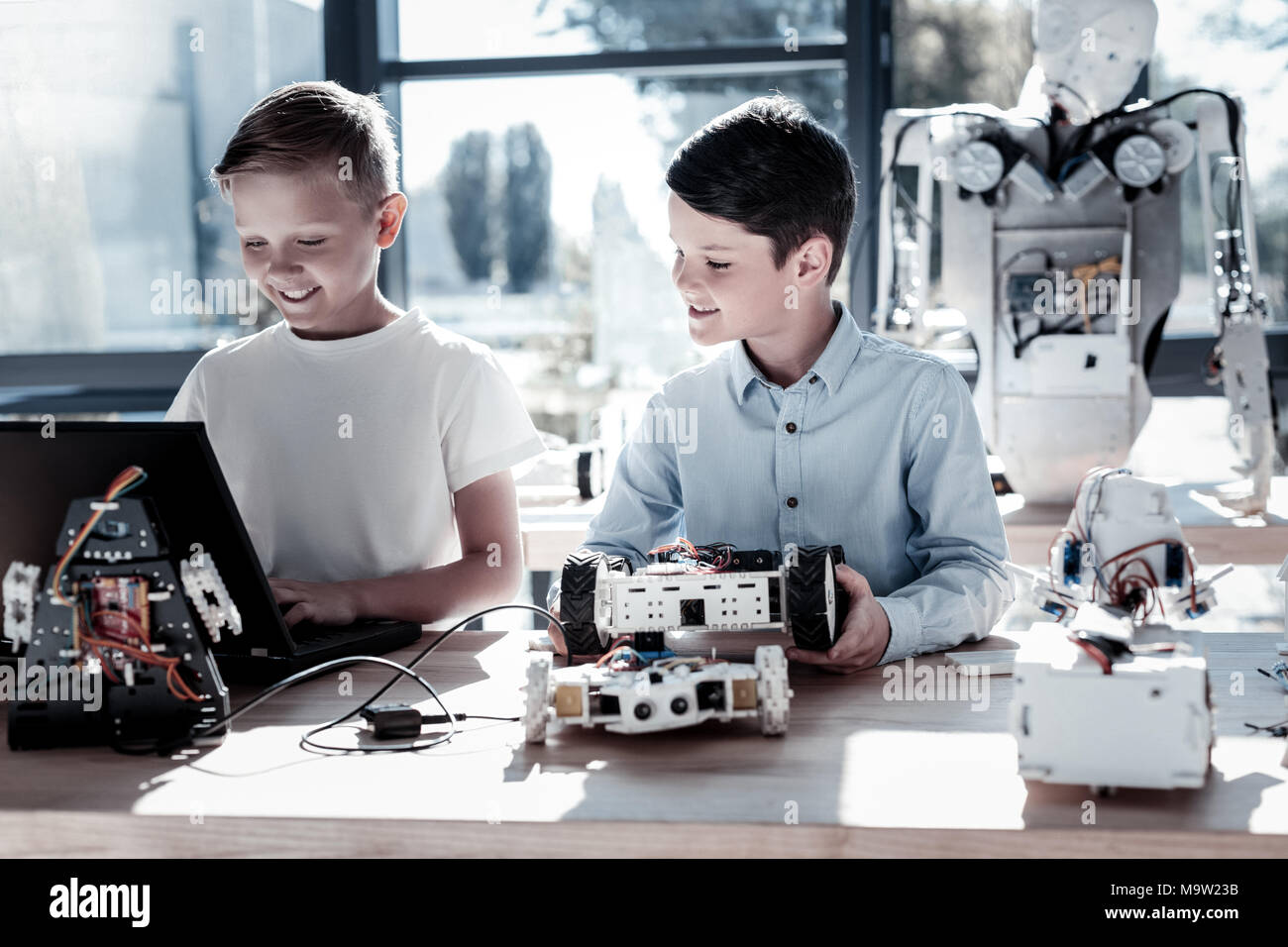 Intelligent kids working on program for their robots Stock Photo - Alamy