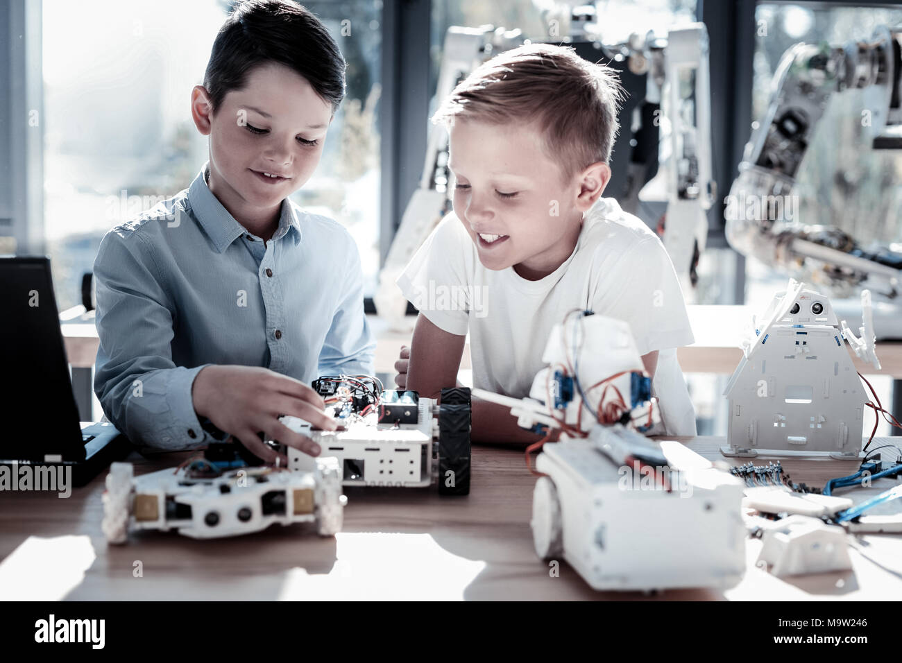 Relaxed kids constructing robotic machines with smiles on their faces ...