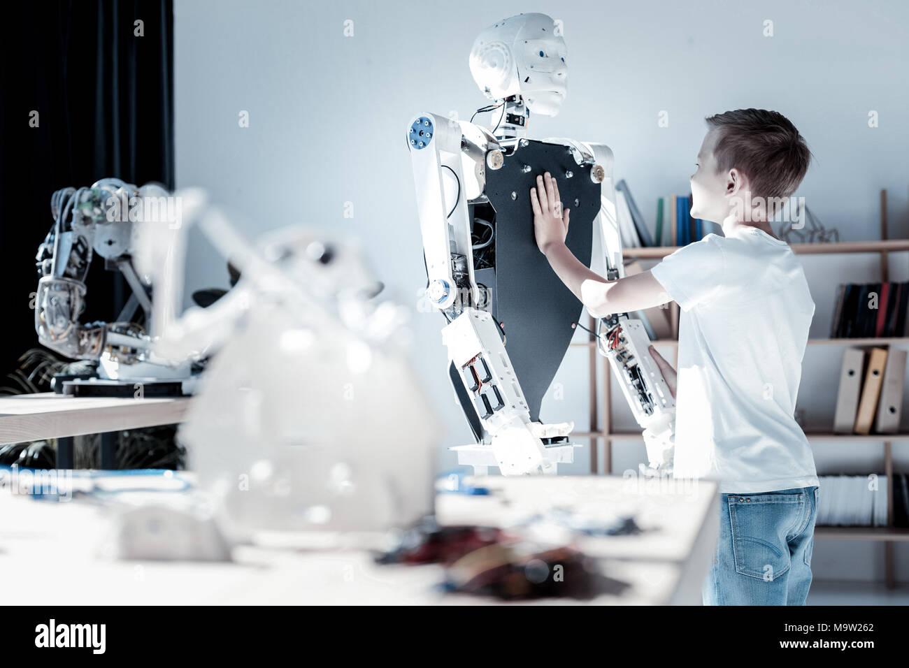 Curious preteen kid touching human like robot Stock Photo - Alamy