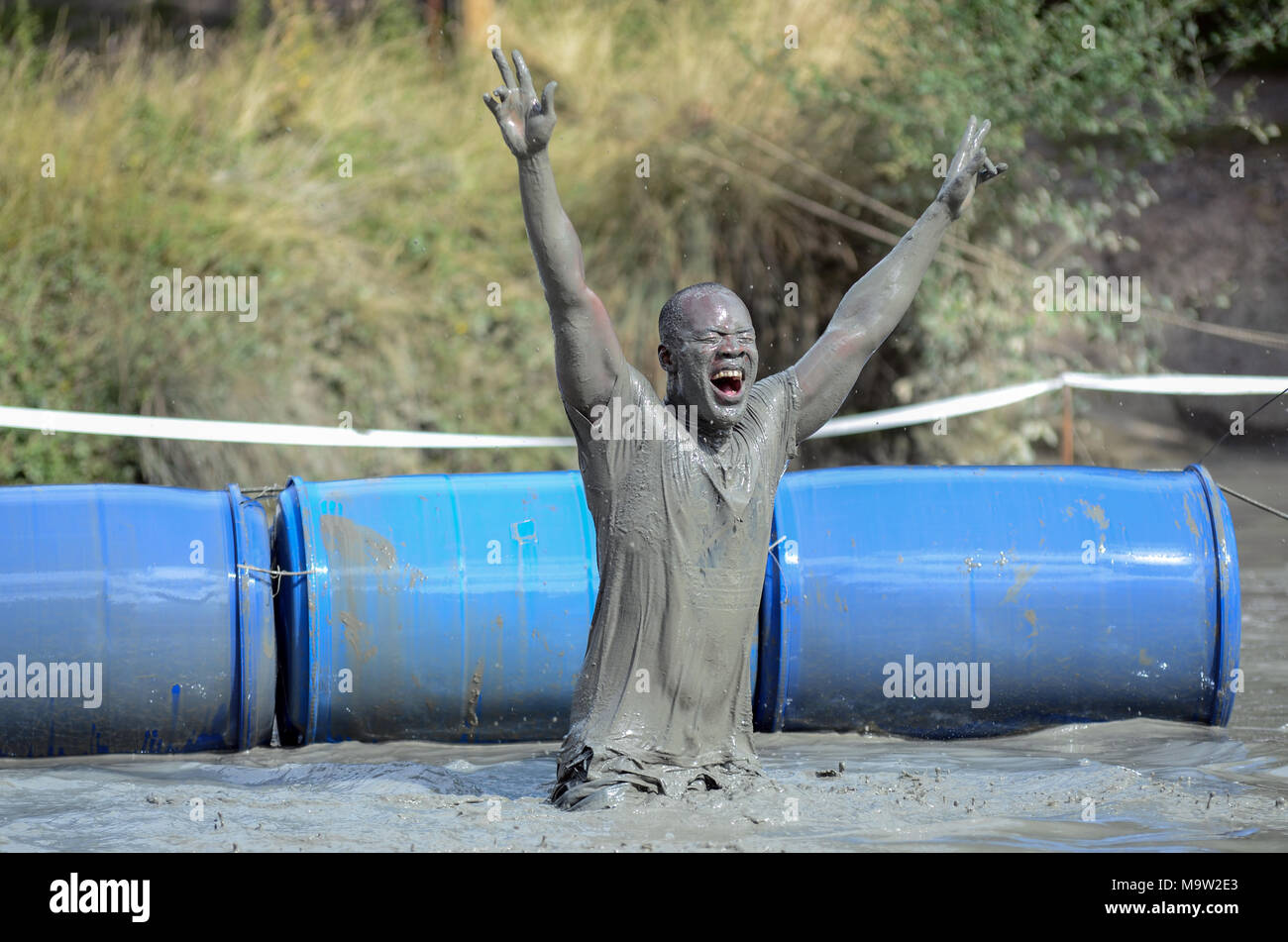 People taking part in a mud run event climbing over objects and getting ...
