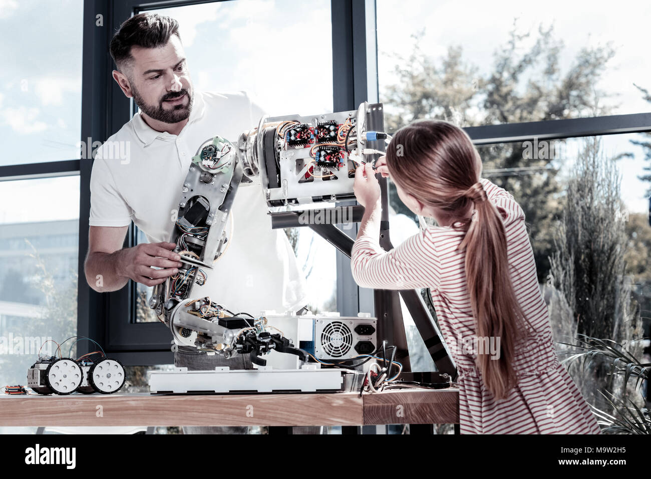 Smart girl helping her teacher with robotic machine Stock Photo - Alamy