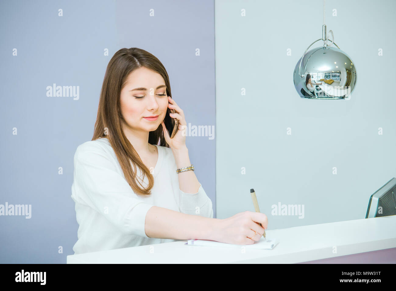 Young female receptionist talking on phone in office Stock Photo - Alamy
