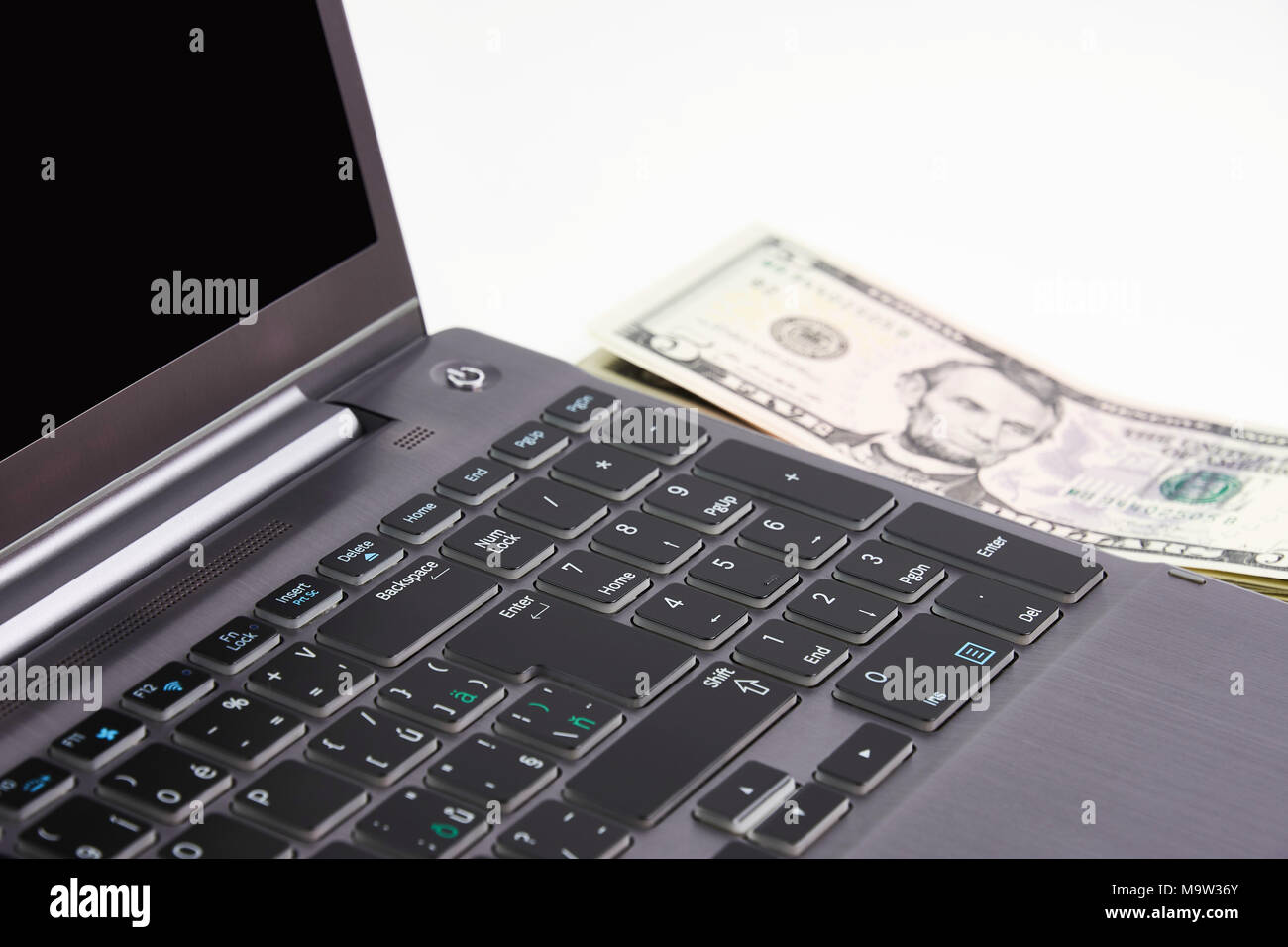 Silver laptop with dollar bills on a white background Stock Photo - Alamy