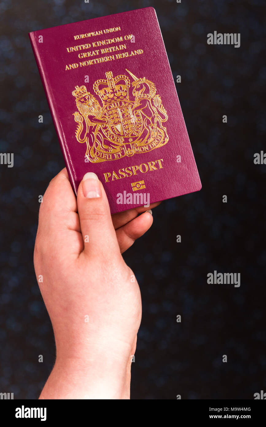Image of a persons hand holding a passport on isolated dark background ...