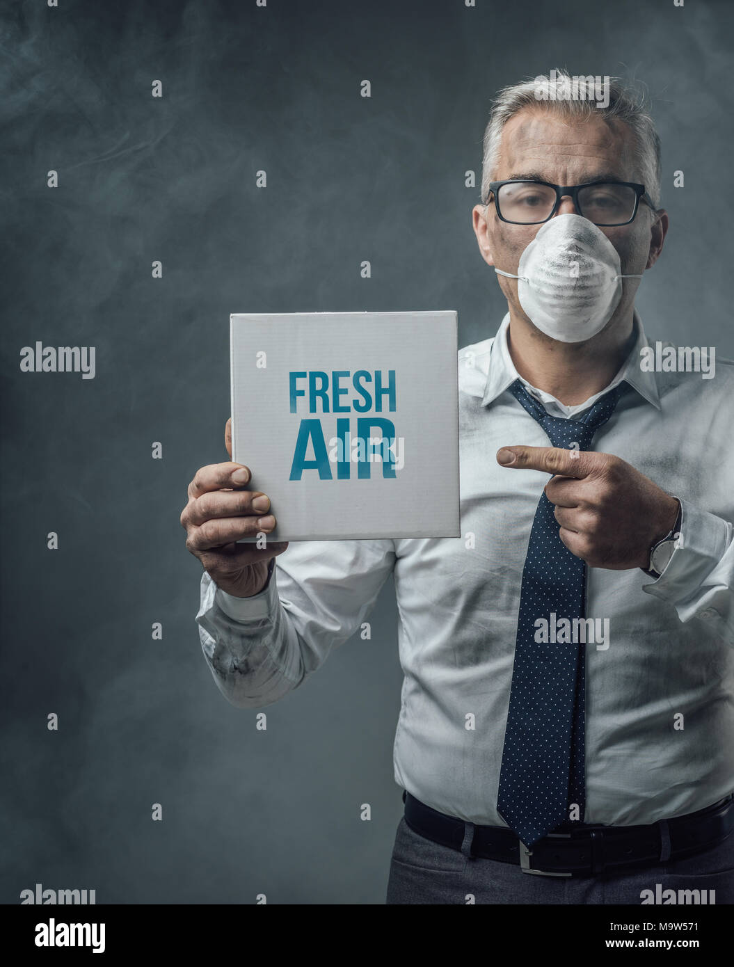 Businessman wearing a mask and polluted air, he is holding a sign with ...