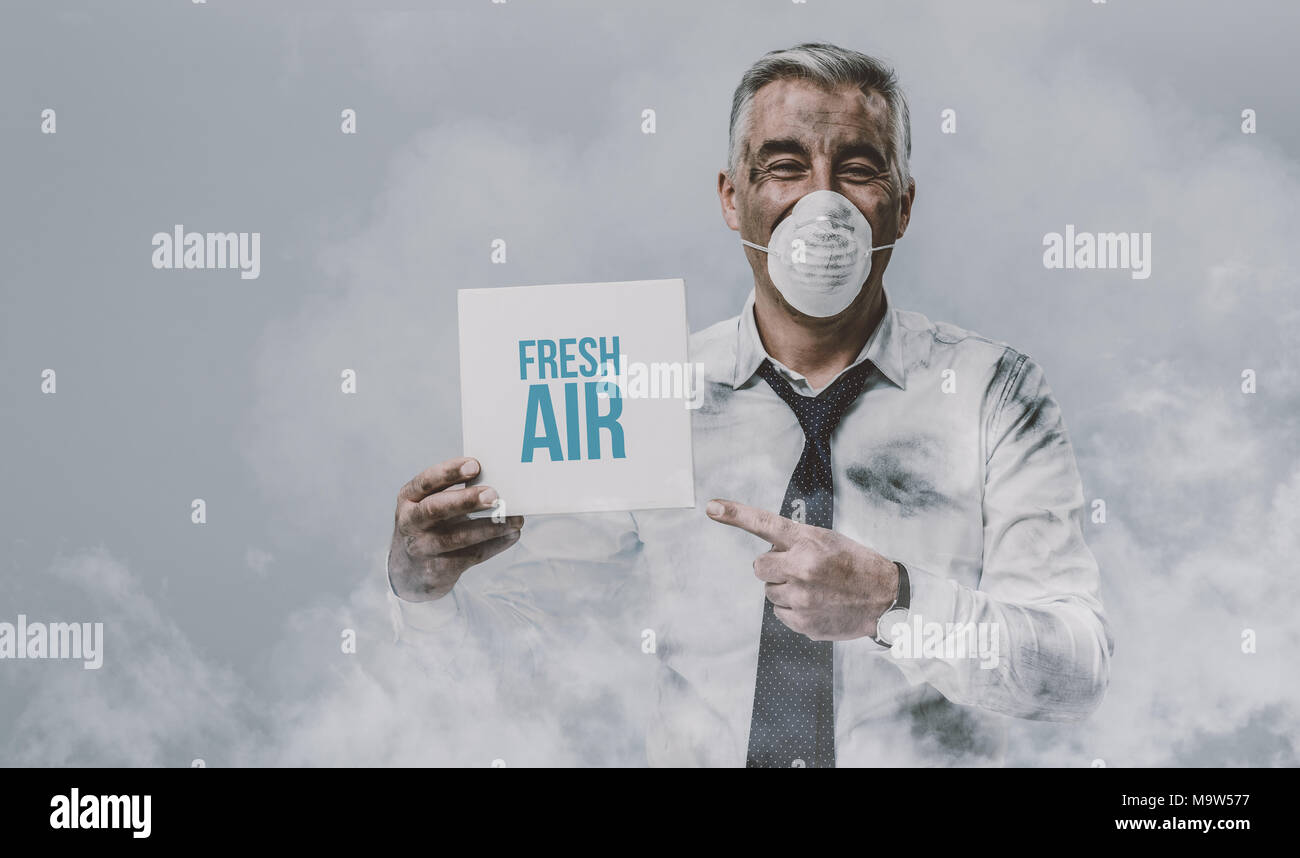 Confident man wearing a pollution mask and holding a fresh air sign ...