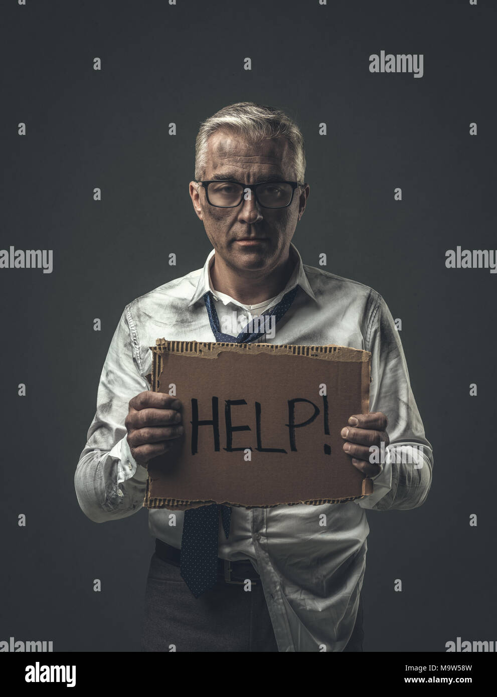 Desperate jobless messy businessman holding a torn cardboard sign and ...