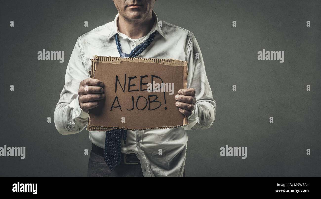 Desperate unemployed messy businessman holding a torn cardboard sign ...