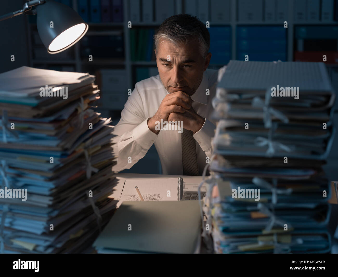 Stressed exhausted business executive working in the office late at ...