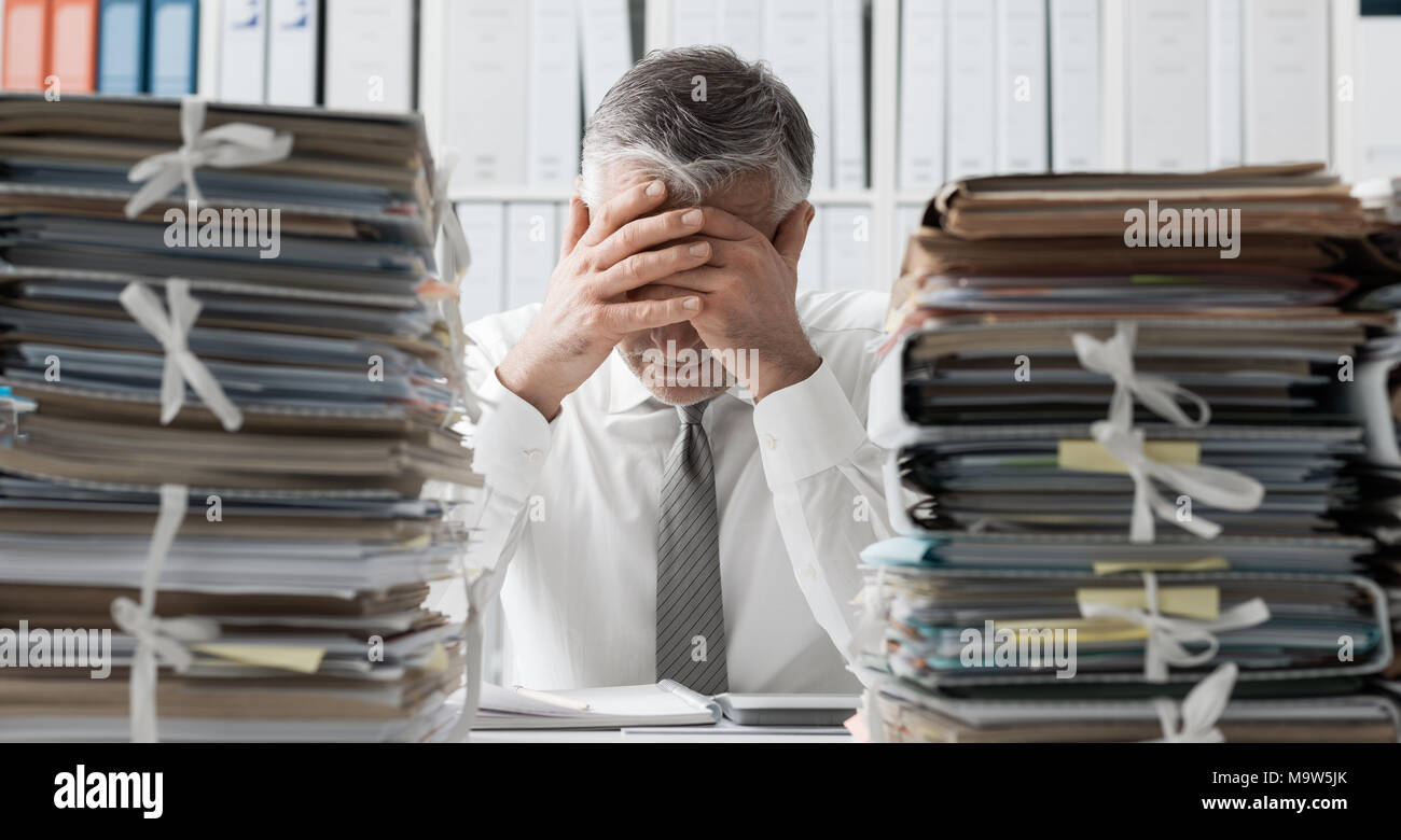 Stressed exhausted business executive in the office overloaded with ...