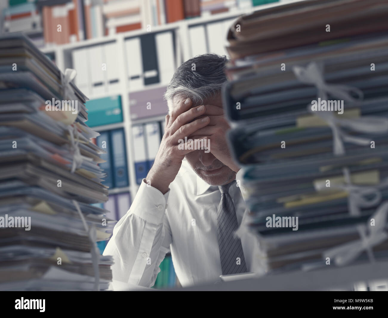 Stressed exhausted business executive in the office overloaded with ...