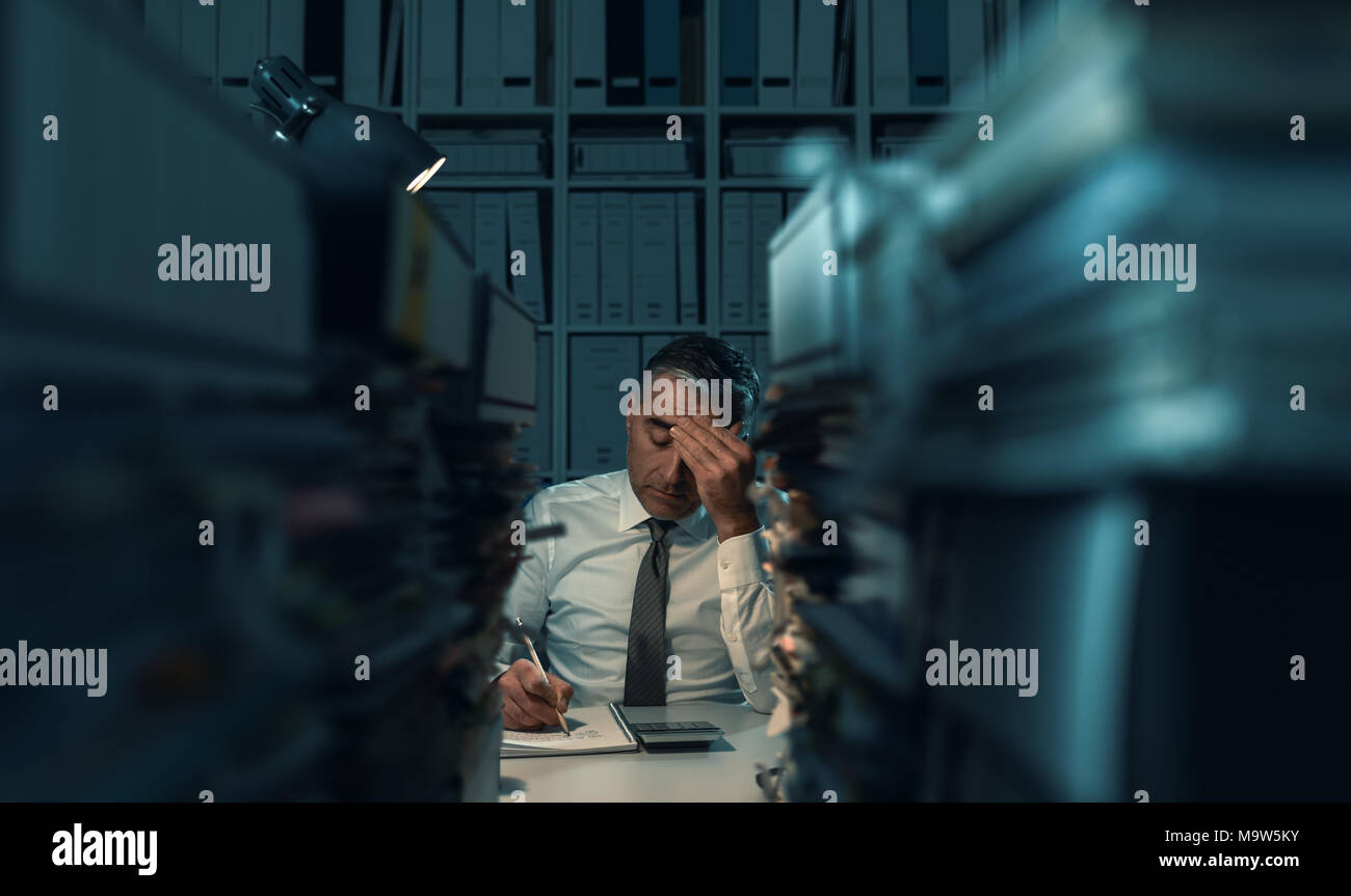 Stressed exhausted business executive working in the office late at ...