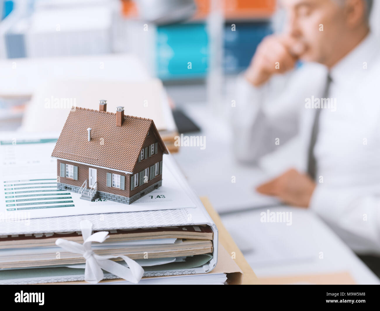 Real estate agent working in the office and piles of paperwork, model ...