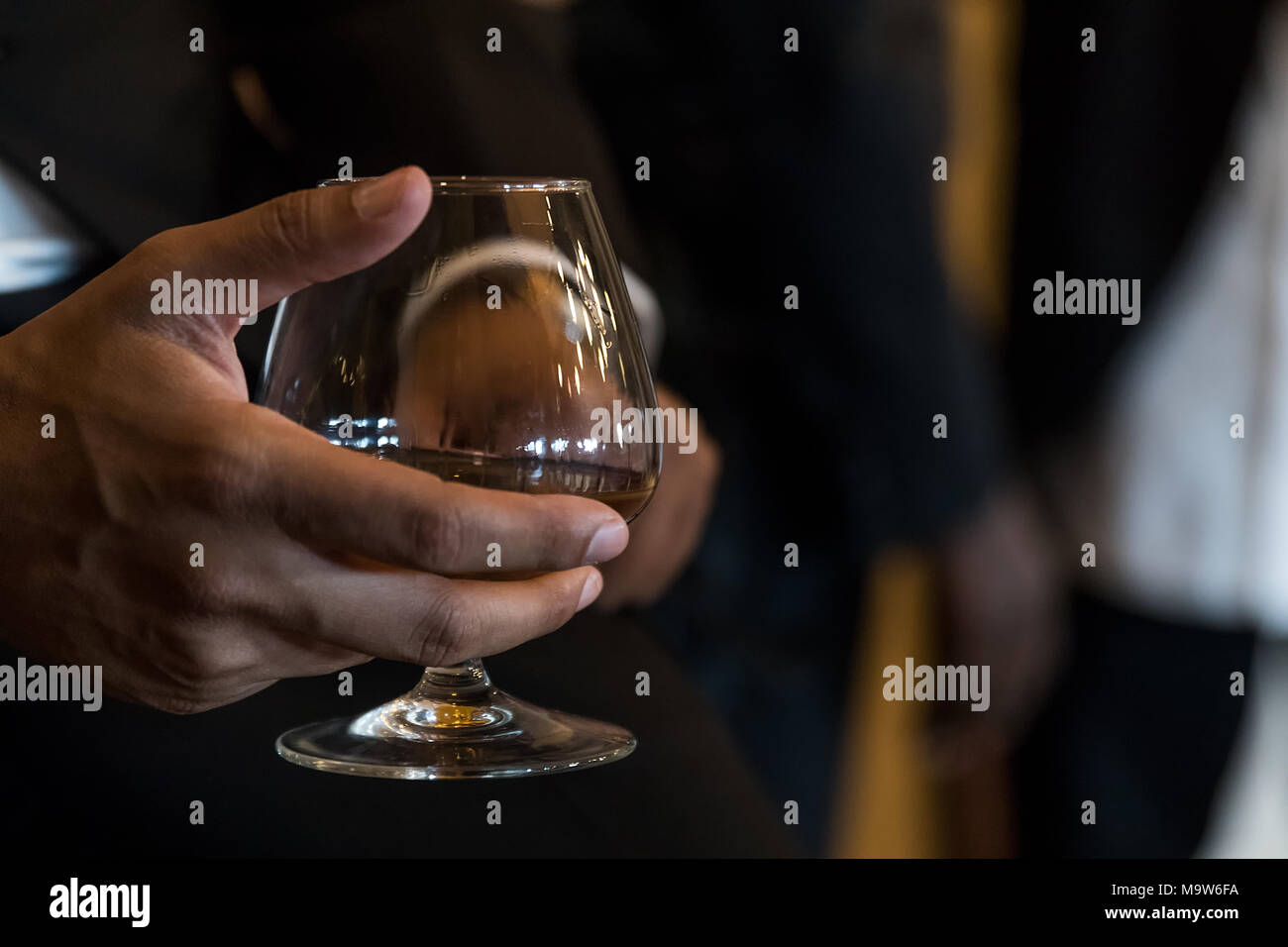 Man grabbing on glass of whiskey dressed in tuxedo Stock Photo - Alamy