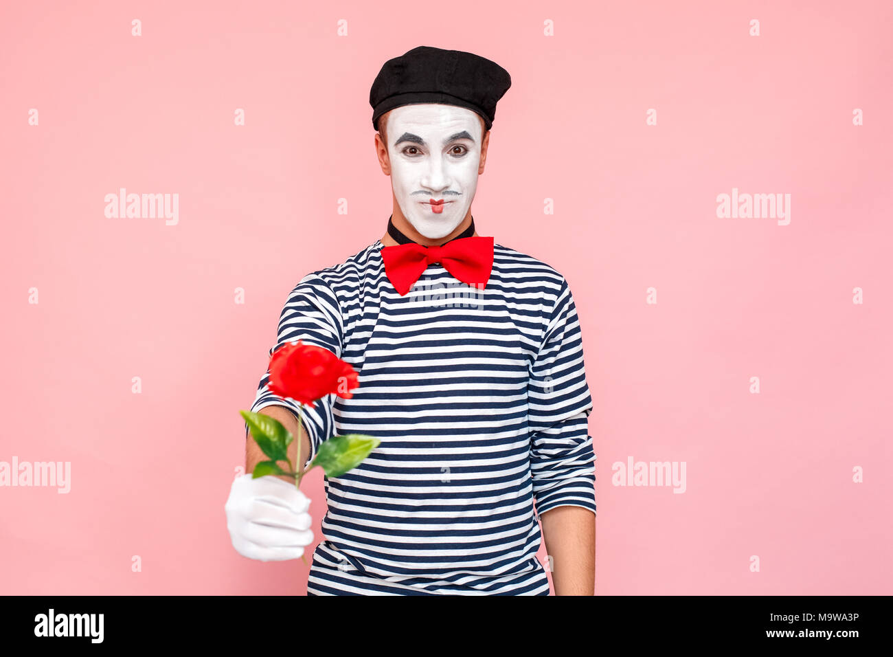 Closeup portrait of handsome man present red rose for you. Clown ...