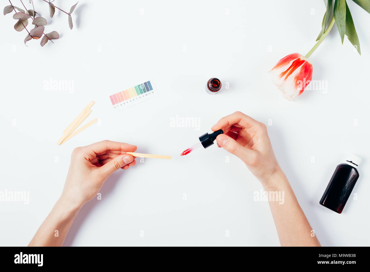 Woman testing cosmetics by using litmus paper. Top view of female hands ...