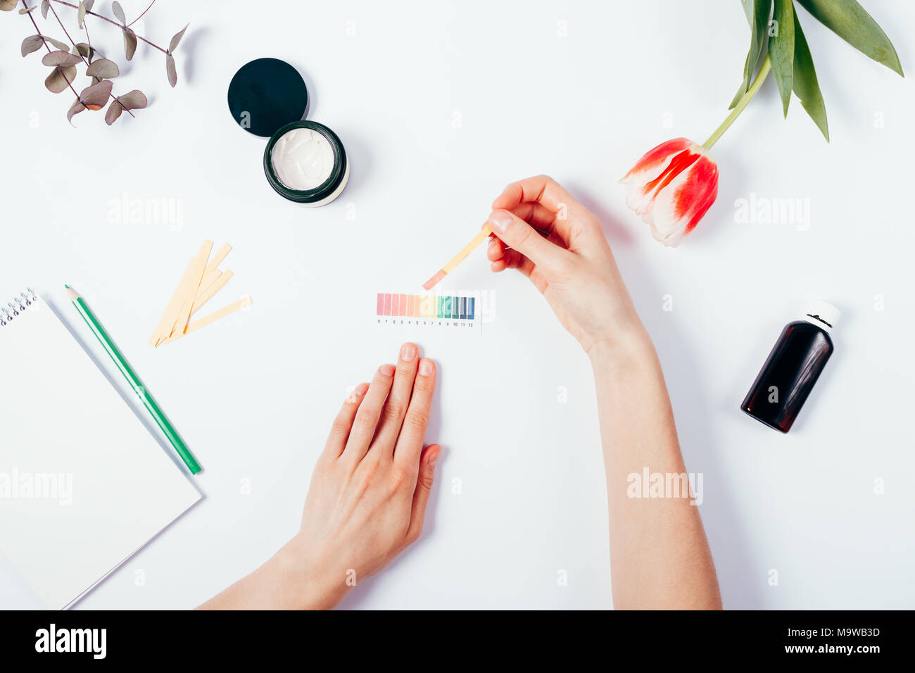 Woman testing cosmetics by using litmus paper and scale. Top view of ...