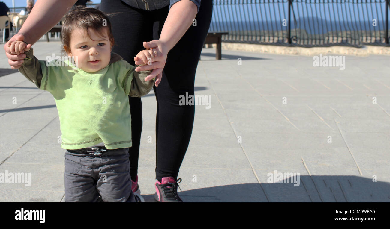 one year old todler learning how to walk with mother Stock Photo - Alamy