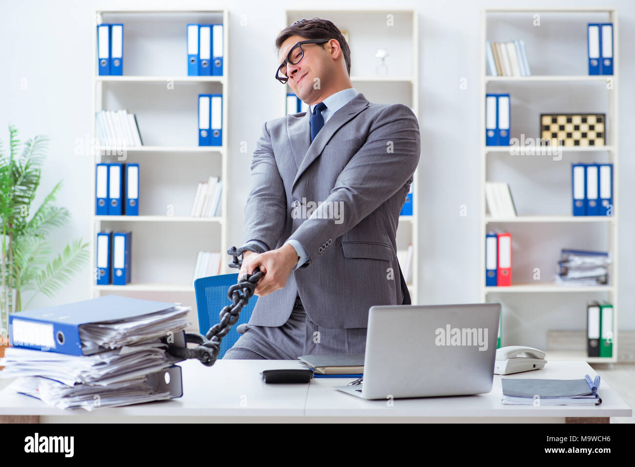 Busy employee chained to his office desk Stock Photo - Alamy
