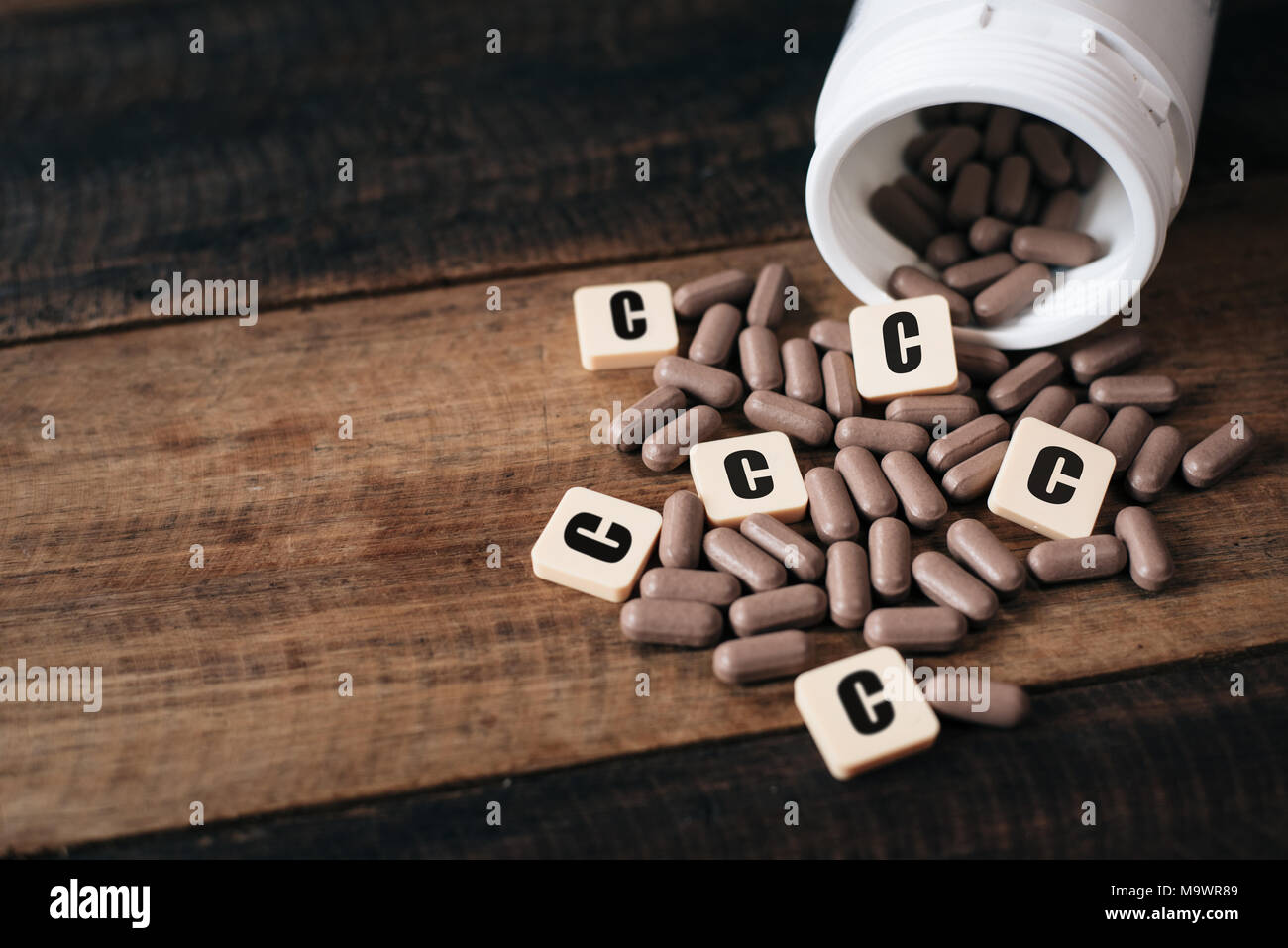 Vitamin C pills and bottle on wooden table with alphabet tiles written ...