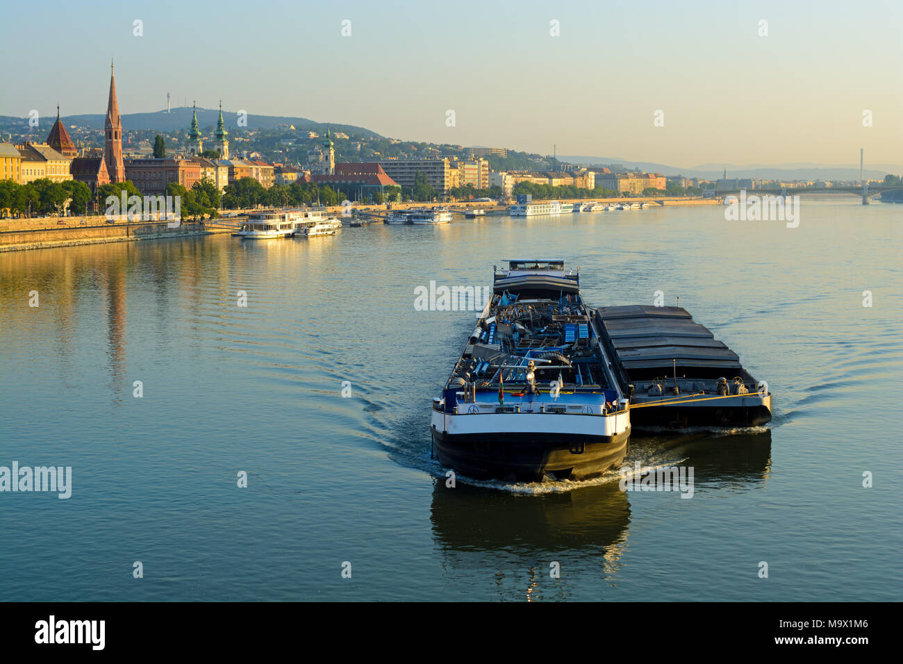 cargo ship carrying a barge side by side along still Danube river in ...