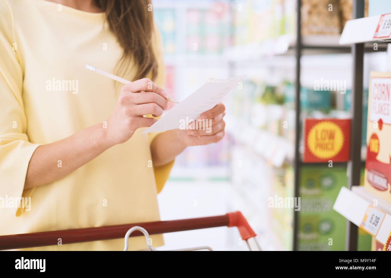 Woman shopping at the grocery store, she is checking items on a list ...