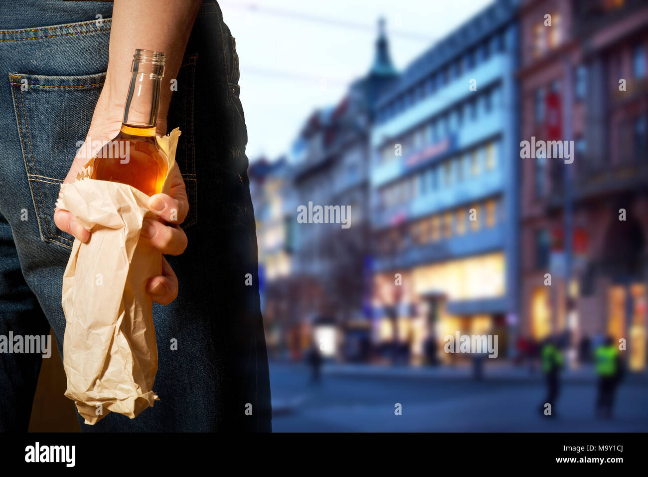 Drinker hiding bottle of spirits in the paper bag Stock Photo - Alamy