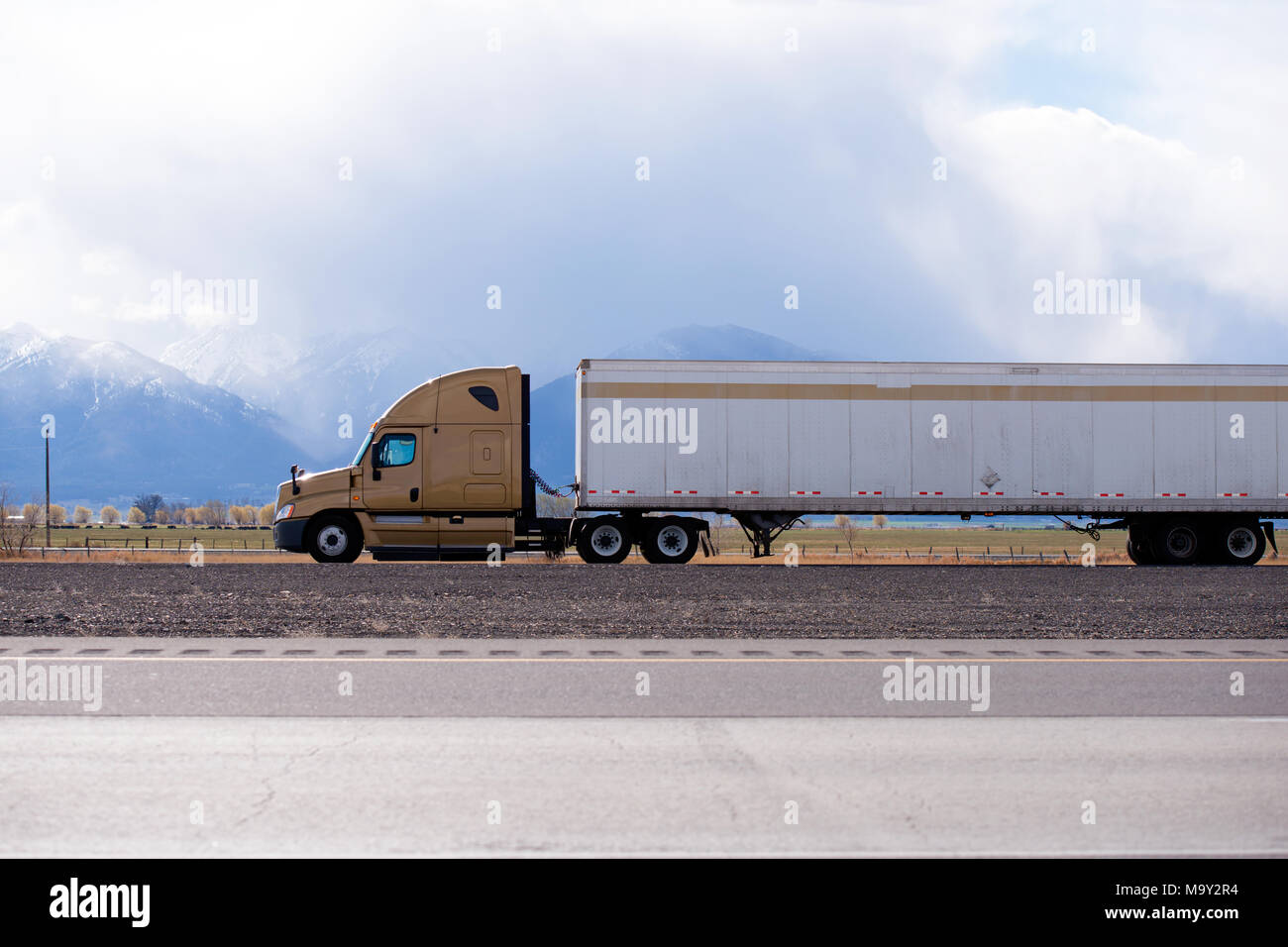 Side view of brown big rig semi truck fleet transporting cargo in long ...