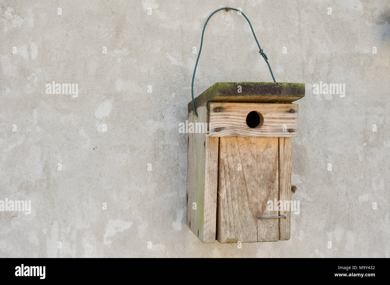 a wooden bird house hanging on a cement wall Stock Photo - Alamy