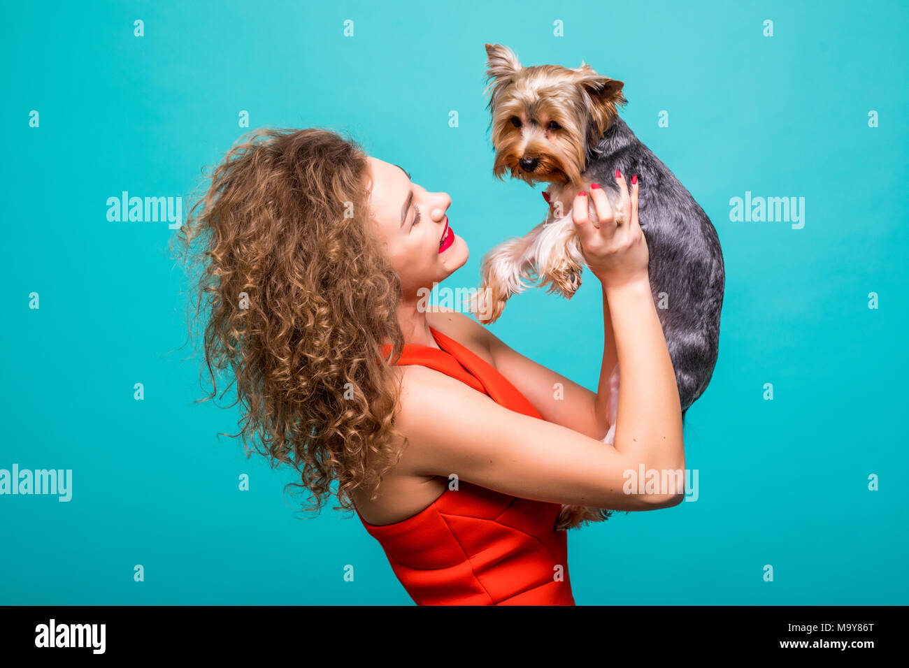 Girl with yorkie dog. Beauty young girl in red dress hug her sweet ...
